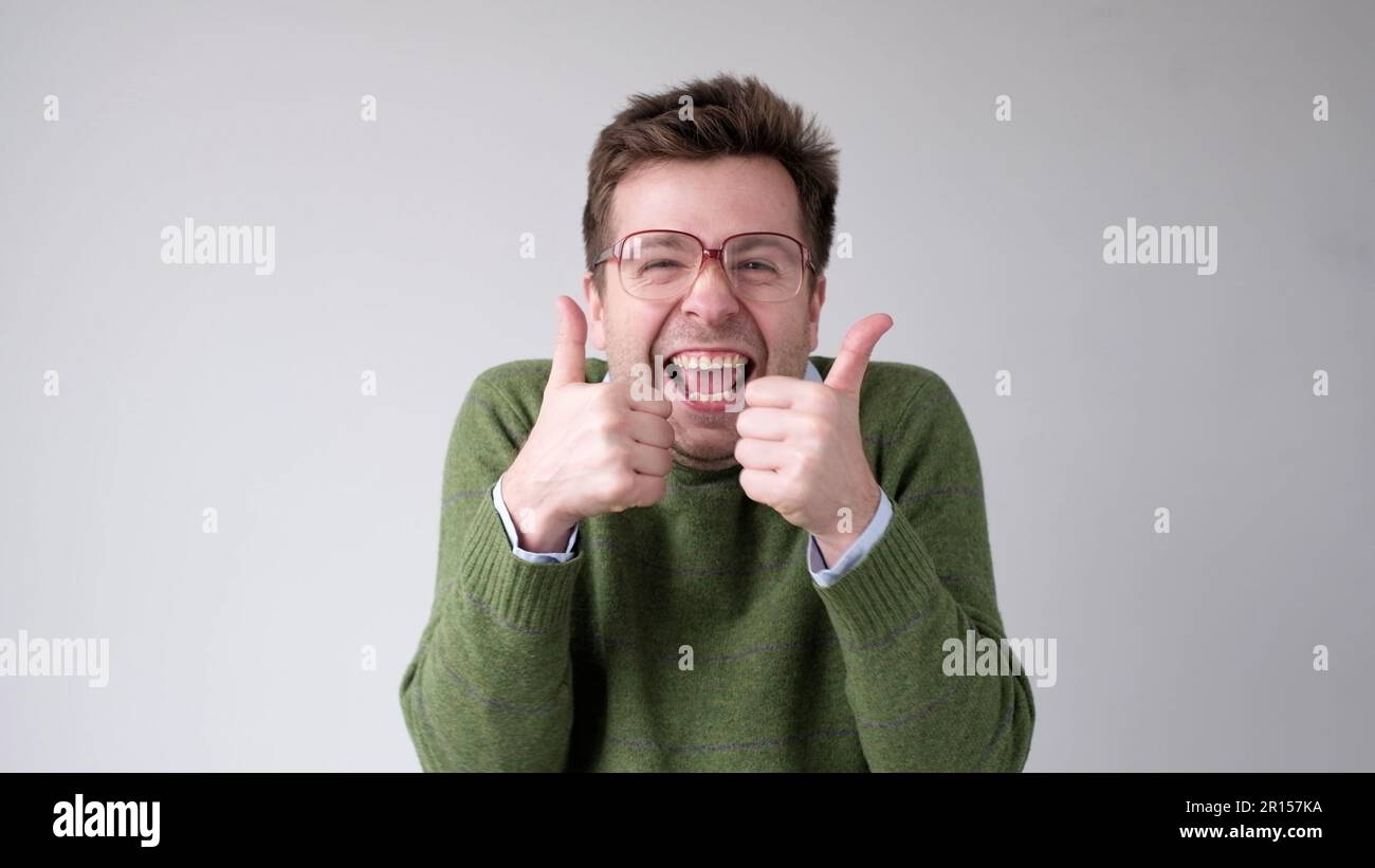 European young man shows a thumbs up. He is thrilled with the result ...