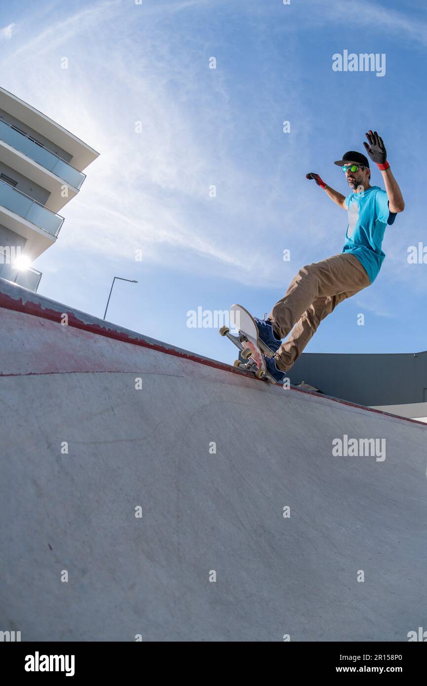 Skateboarder doing frontside five-o grind trick in concrete skatepark ...