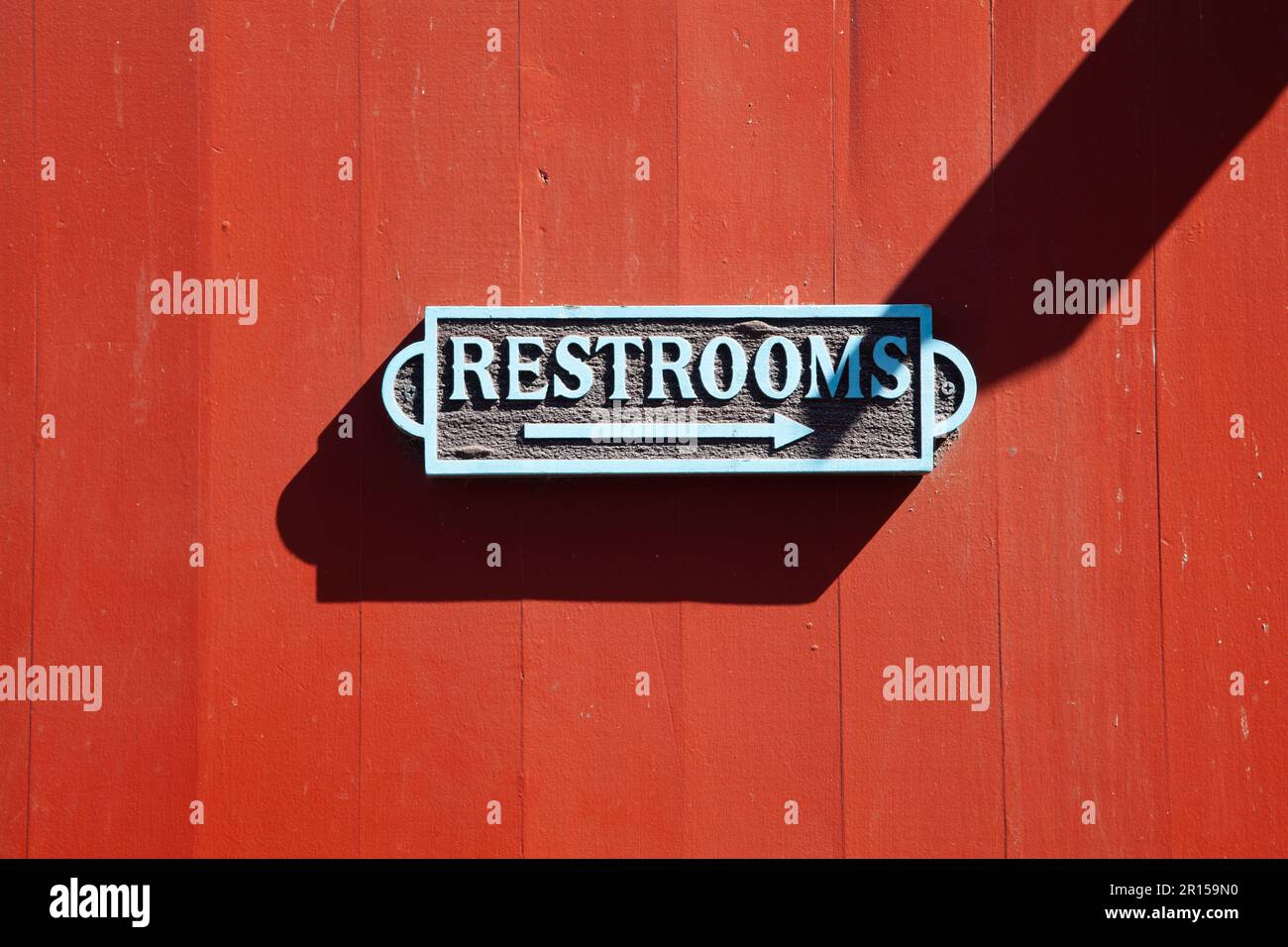 sign restroom in metal at a red wall with shadow Stock Photo - Alamy
