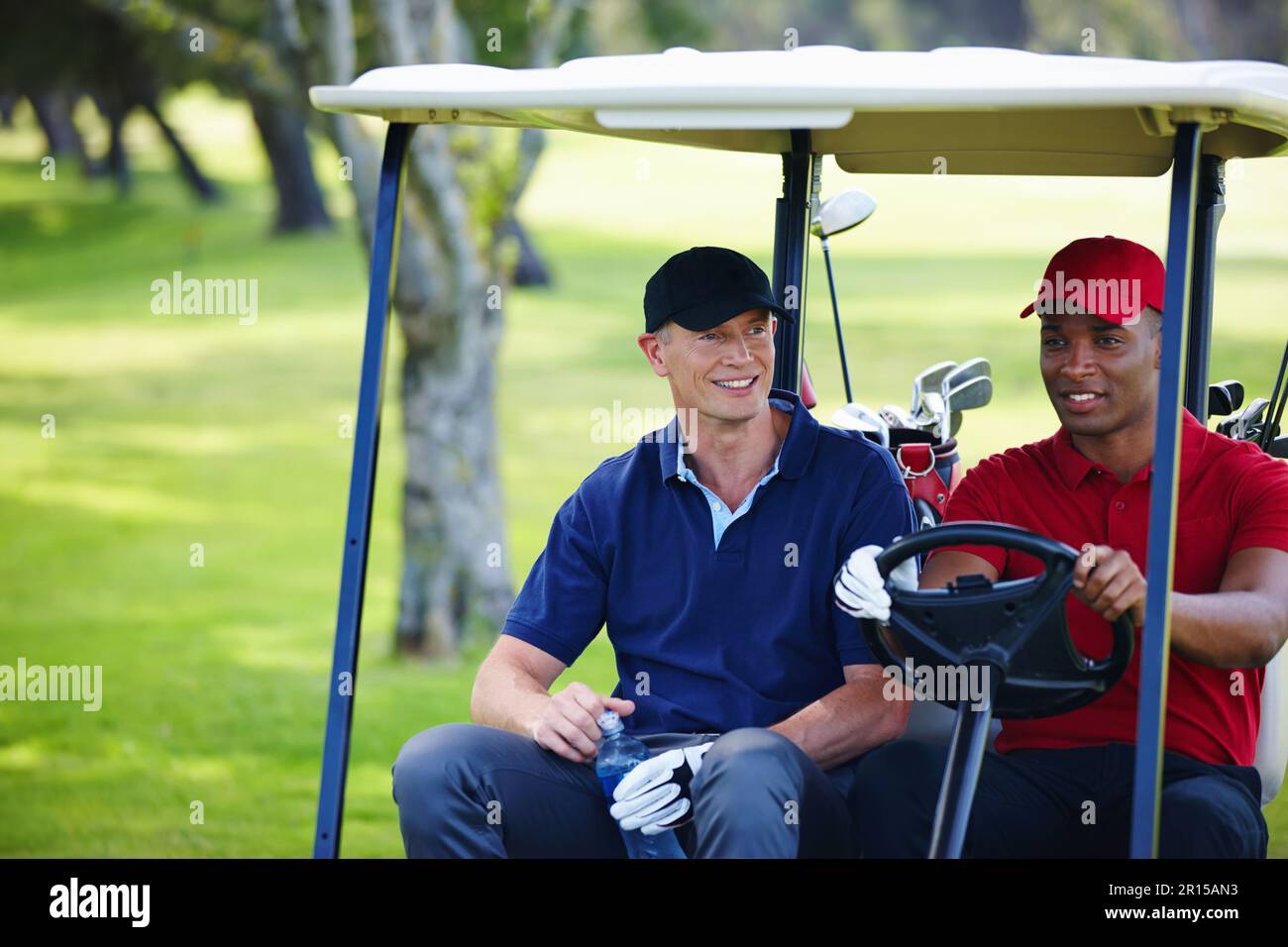 Out for a drive. two men in a cart driving across a golf course Stock ...