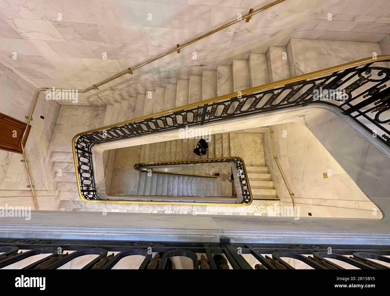 A rectangular stairs looking down. There is one person on the stairs ...