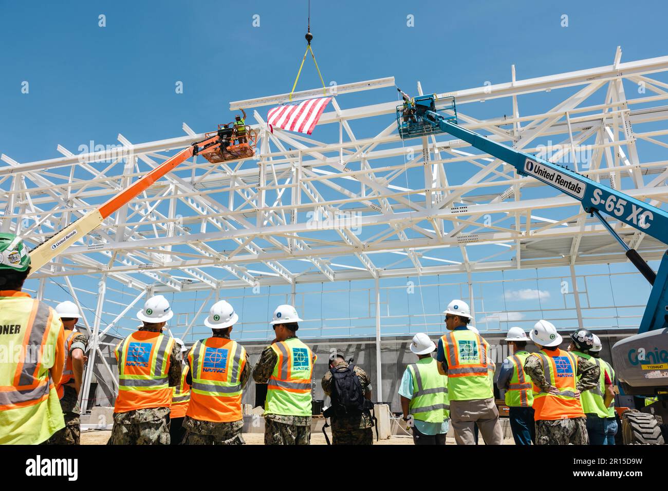 Construction crew members, Marines and Sailors watch as the final beam ...