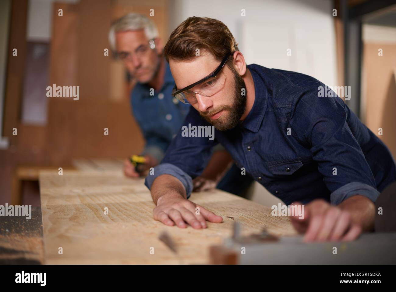 Learning the trade. a father and son working together on a carpentry ...