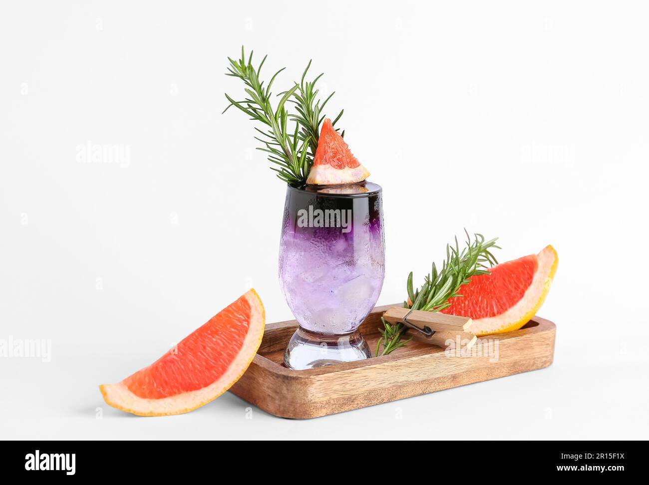 Glass of purple gin and tonic with grapefruit and rosemary on white ...