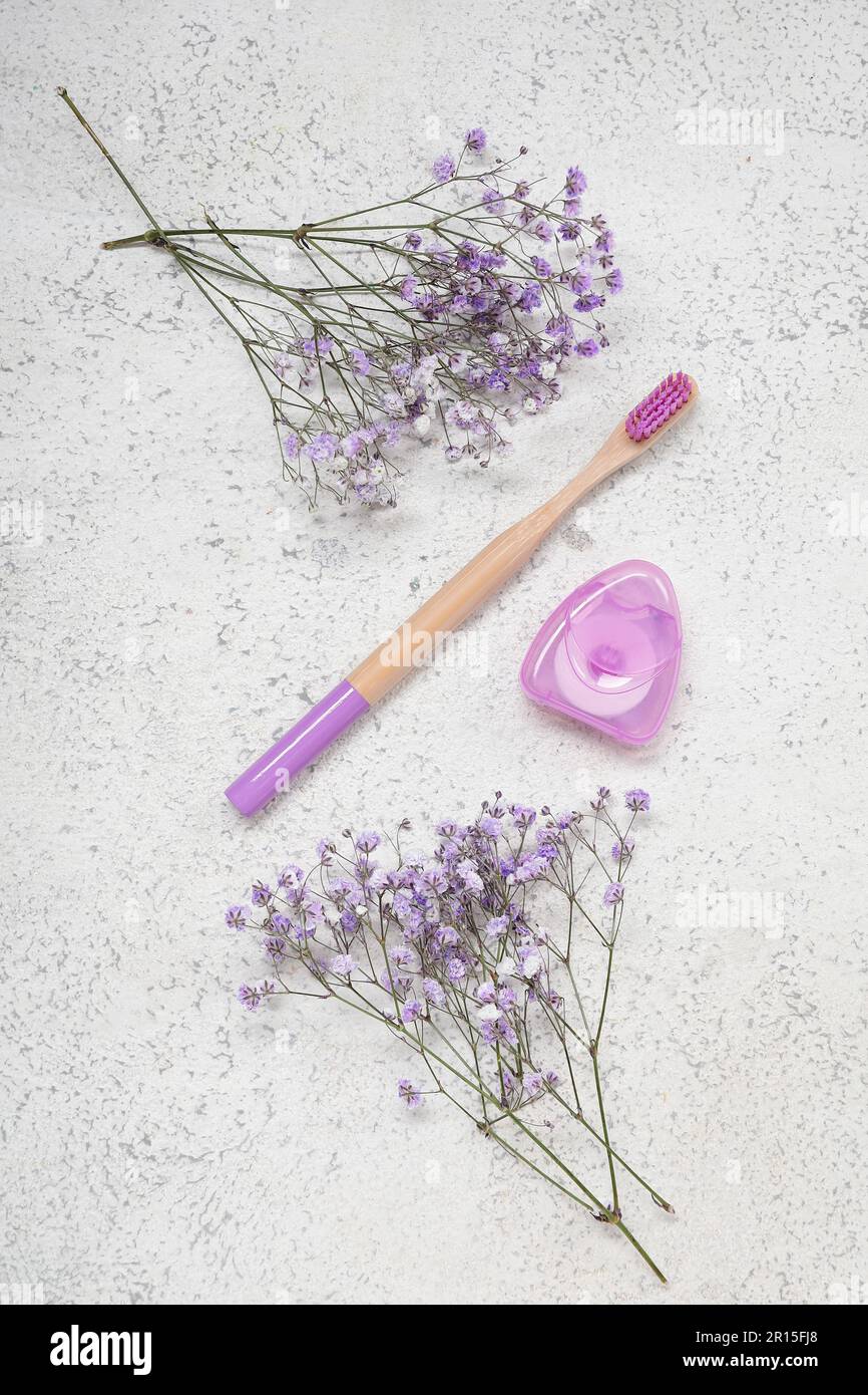 Dental floss with bamboo toothbrush and flowers on grunge background ...
