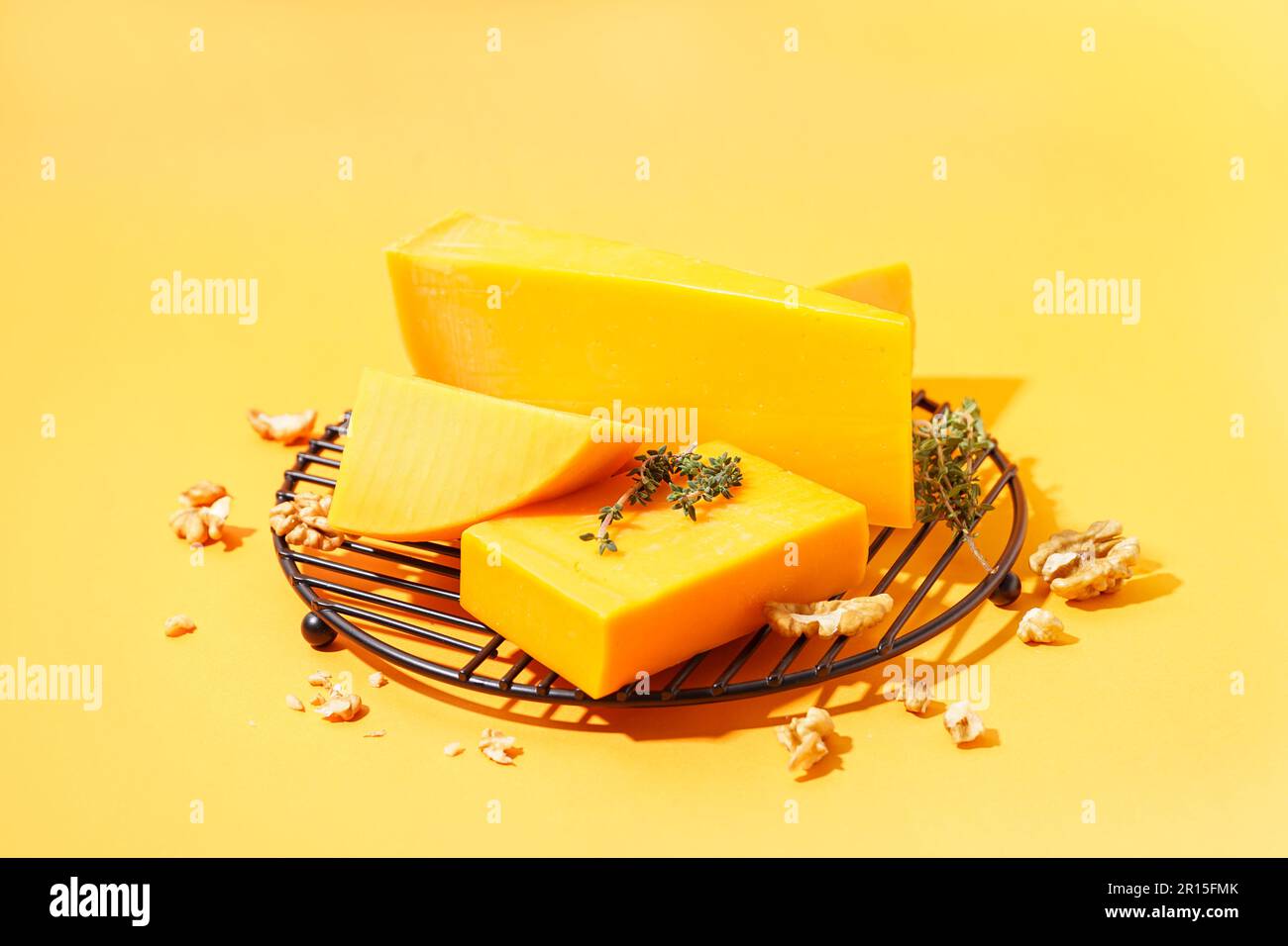 Stand with tasty cheddar cheese, thyme and nuts on orange background ...