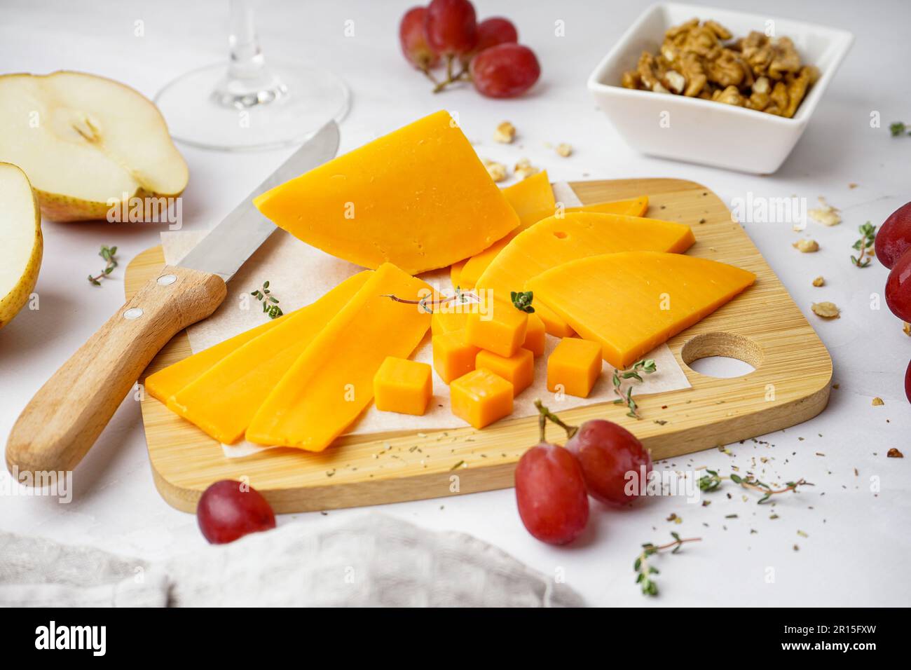 Wooden board with tasty cheddar cheese on light background Stock Photo ...