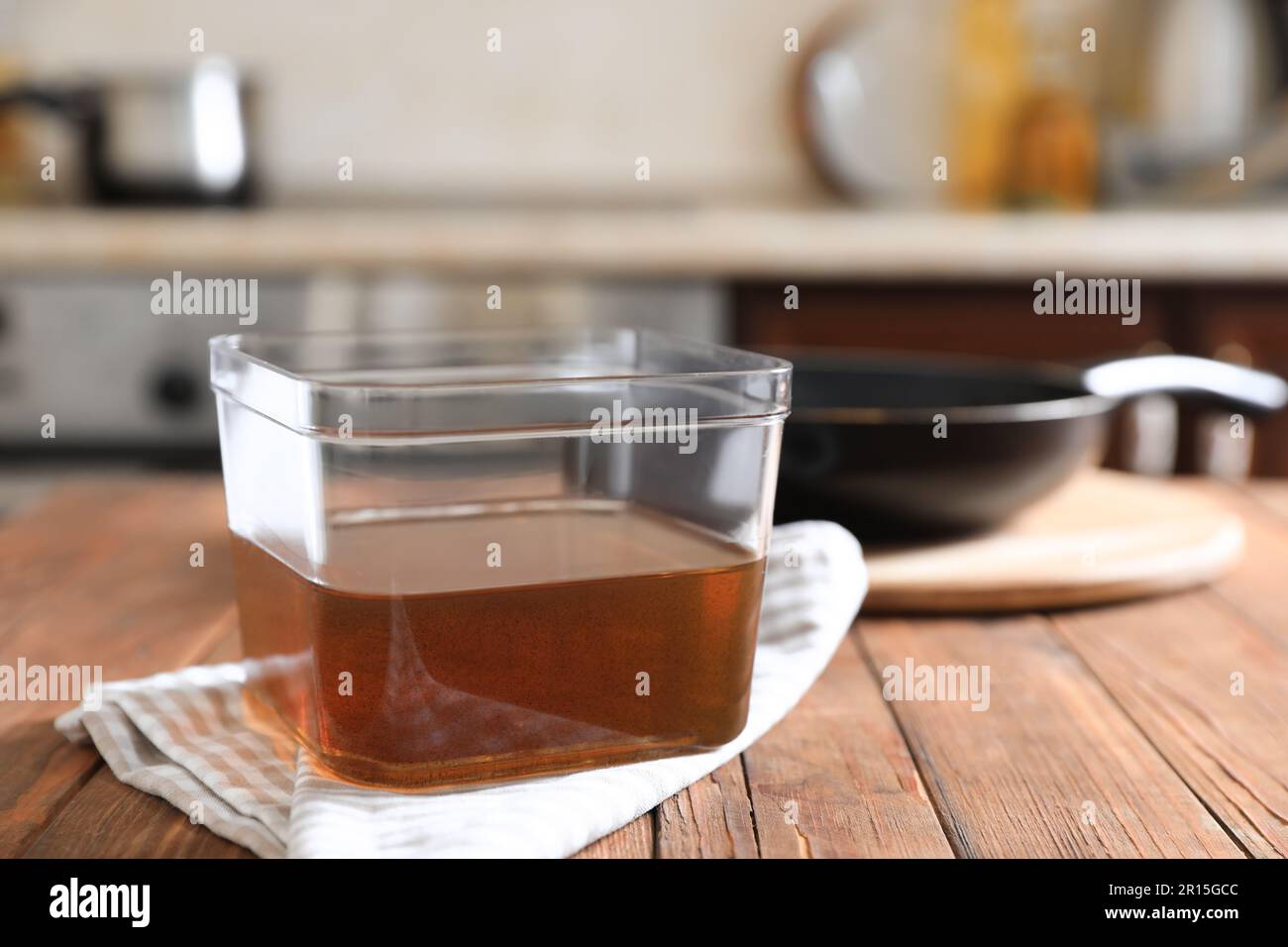 Container with used cooking oil on wooden table in kitchen Stock Photo ...