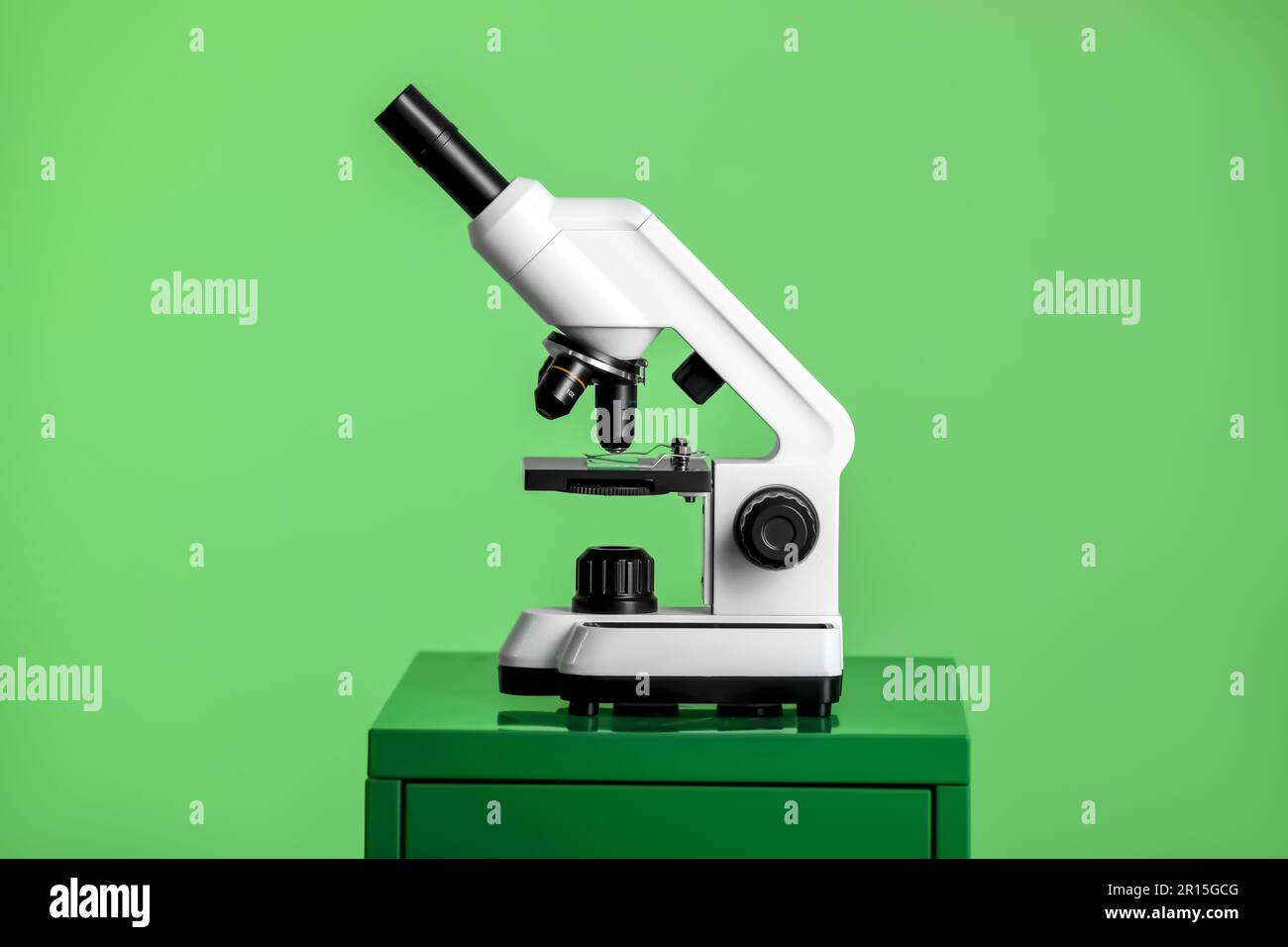 Modern medical microscope on lab drawer against green background Stock ...