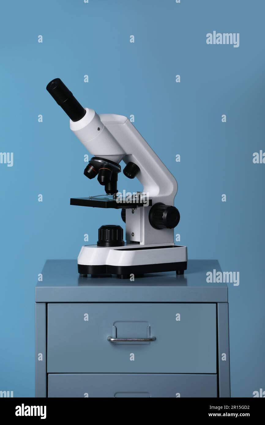 Microscope on laboratory cabinet against blue background Stock Photo ...