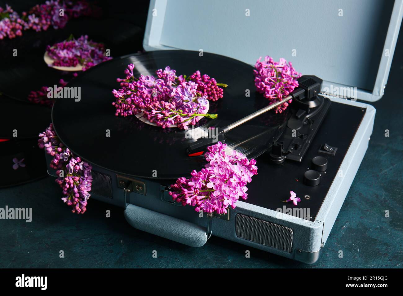 Record player with vinyl disk and beautiful lilac flowers on dark color ...