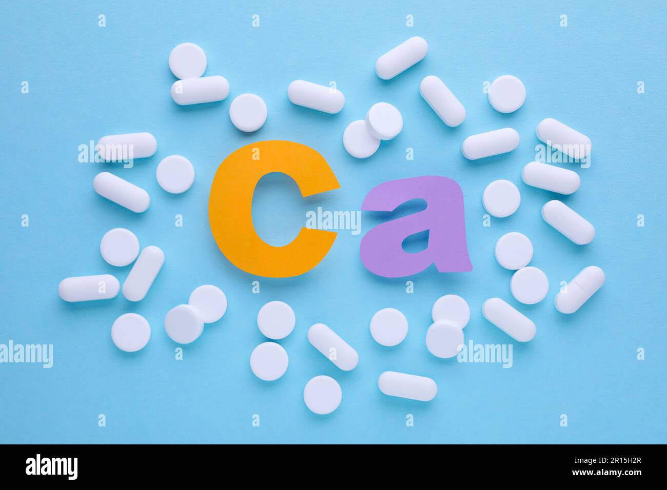 Calcium symbol made of colorful letters and white pills on light blue ...