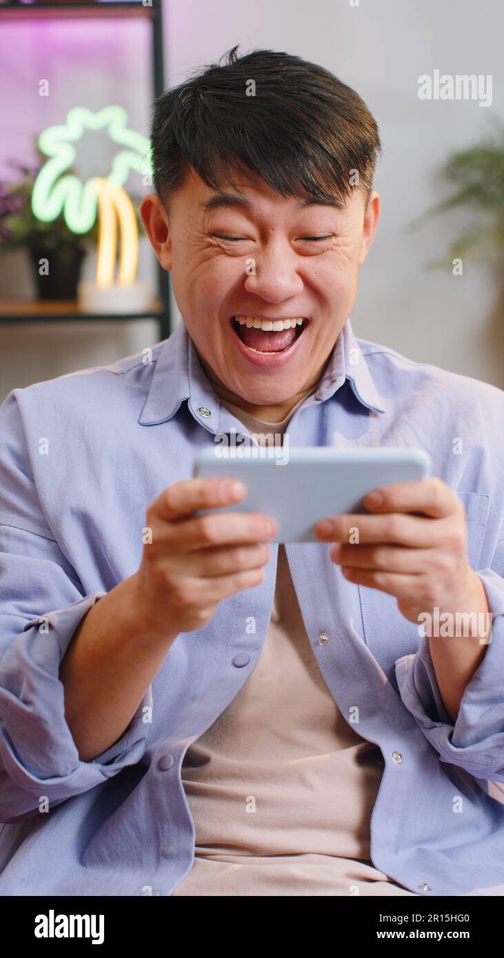 Worried asian winner man playing racing or shooter video games on ...