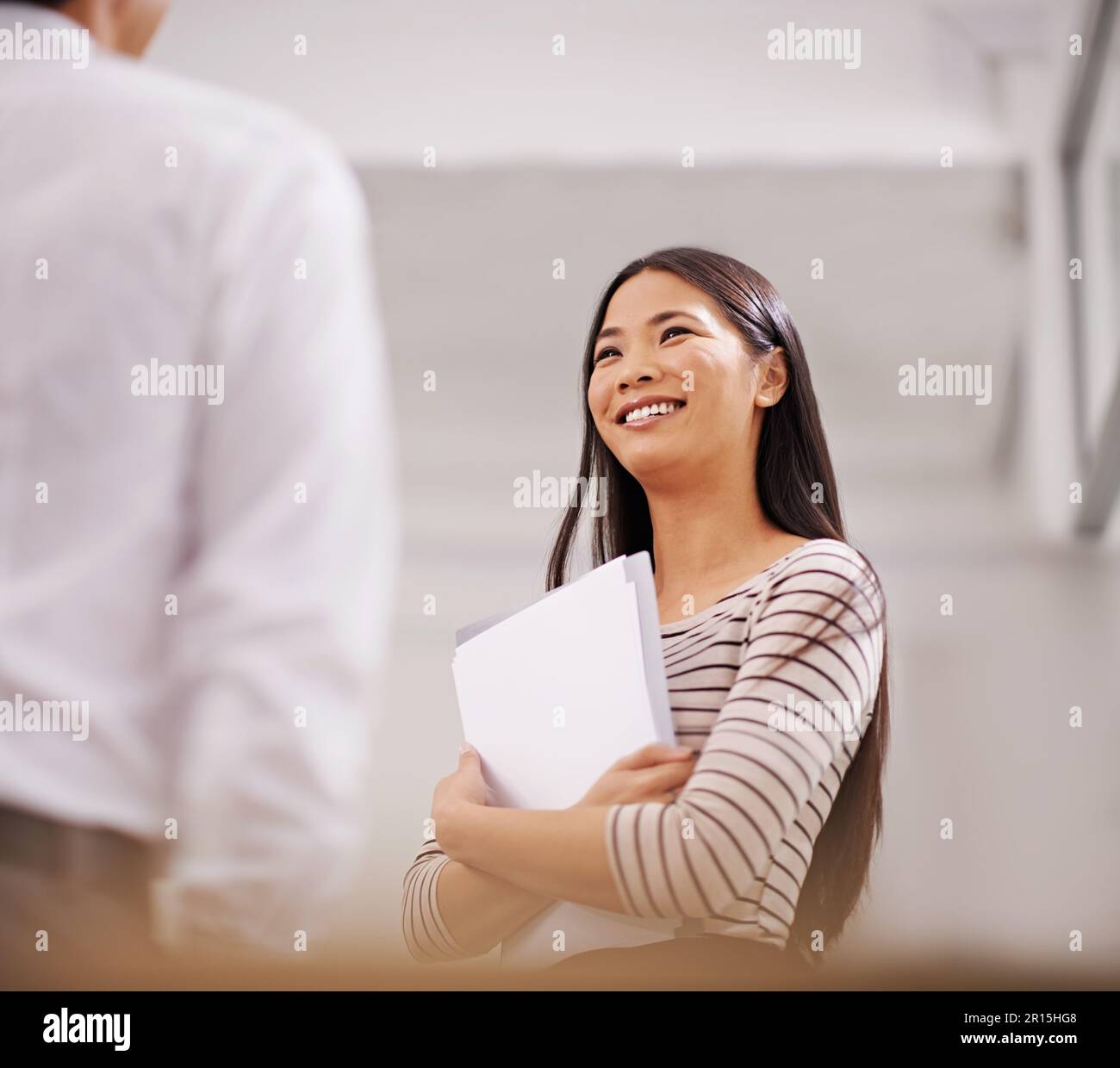 Do you have a few seconds to spare. a young asian businesswoman holding documents speaking to a ...