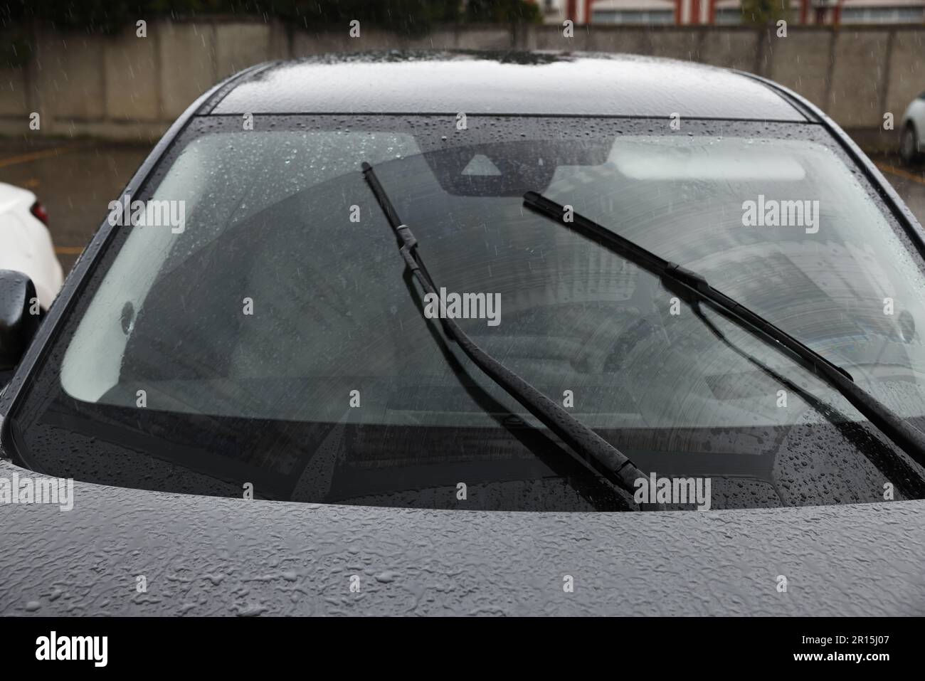 Car wipers cleaning water drops from windshield glass outdoors, closeup ...
