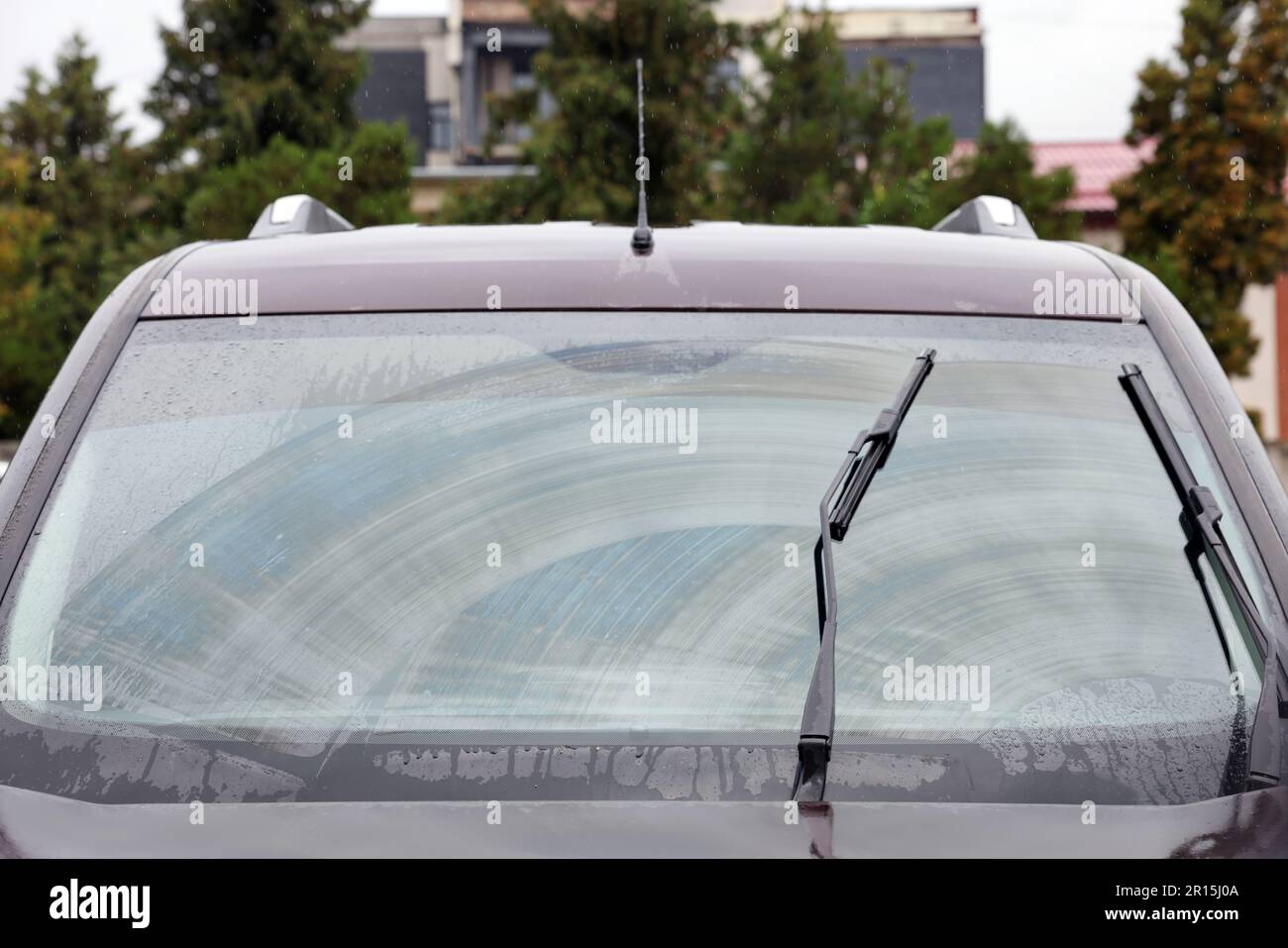Car wipers cleaning water drops from windshield glass outdoors, closeup ...