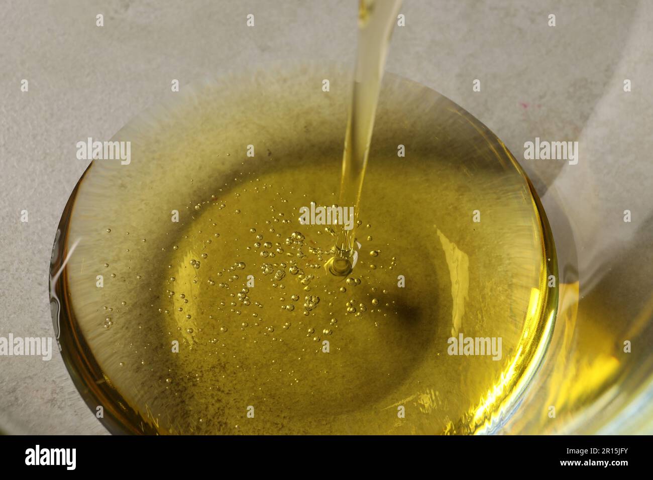 Pouring cooking oil into glass bowl, closeup Stock Photo - Alamy