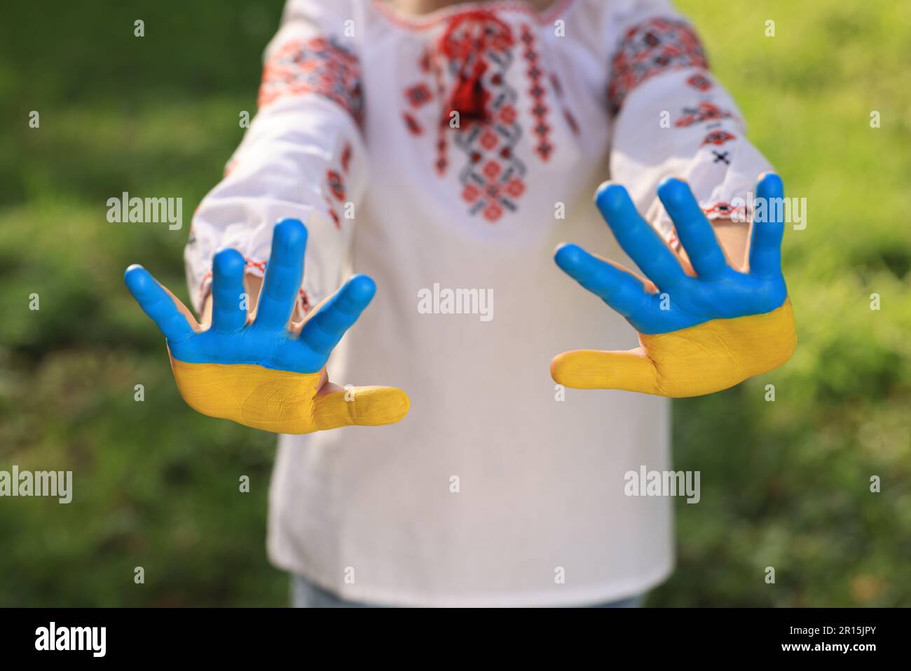 Little girl with hands painted in Ukrainian flag color outdoors, focus ...