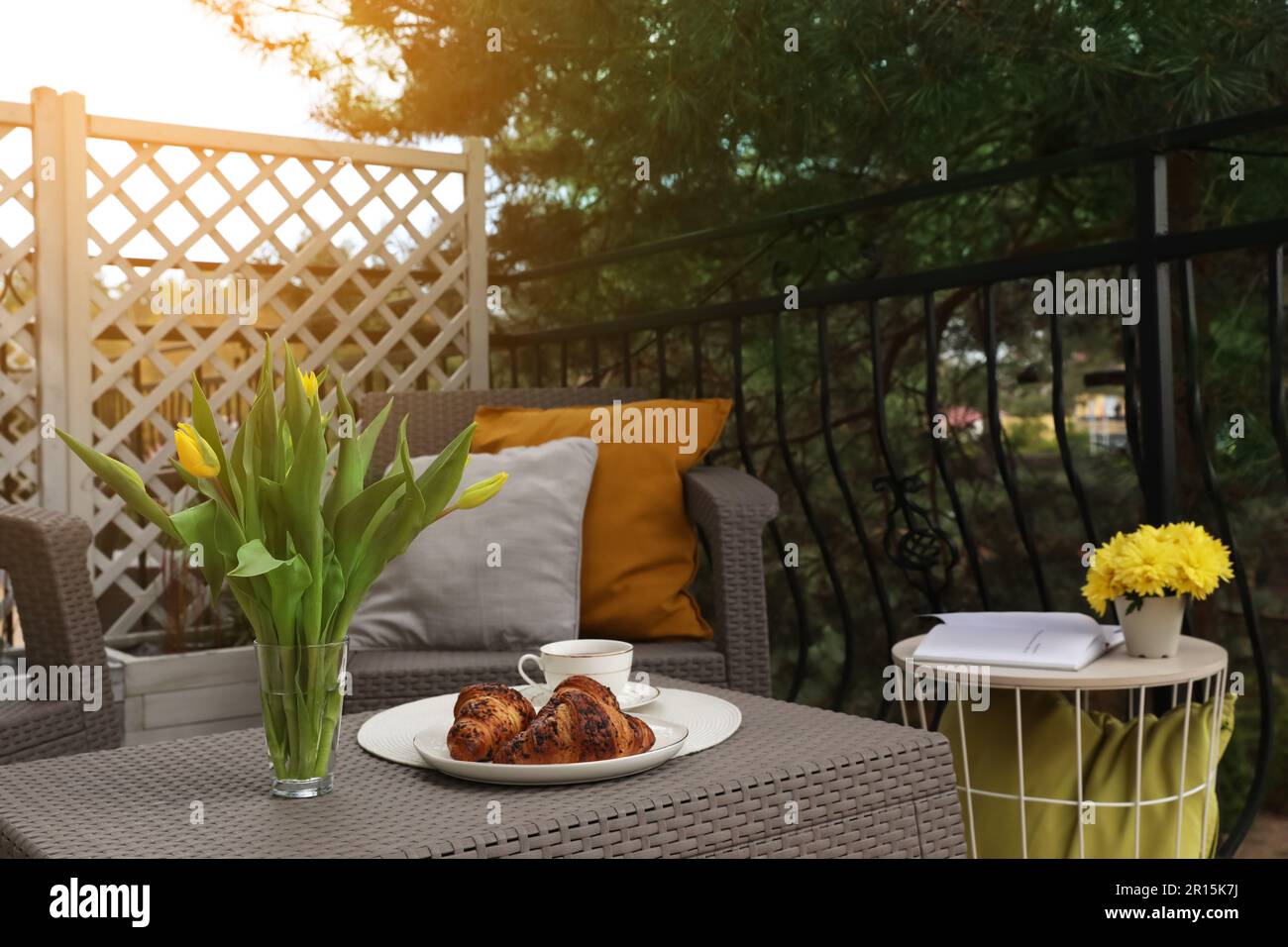 Different pillows, blanket, breakfast and tulips on rattan garden ...