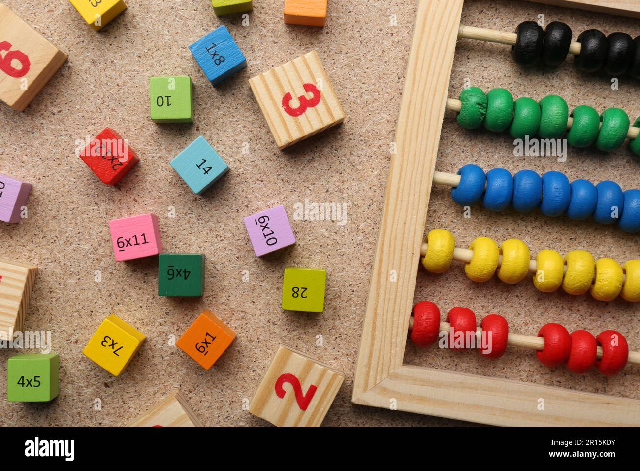 Wooden cubes with numbers and multiplications near abacus on fiberboard ...