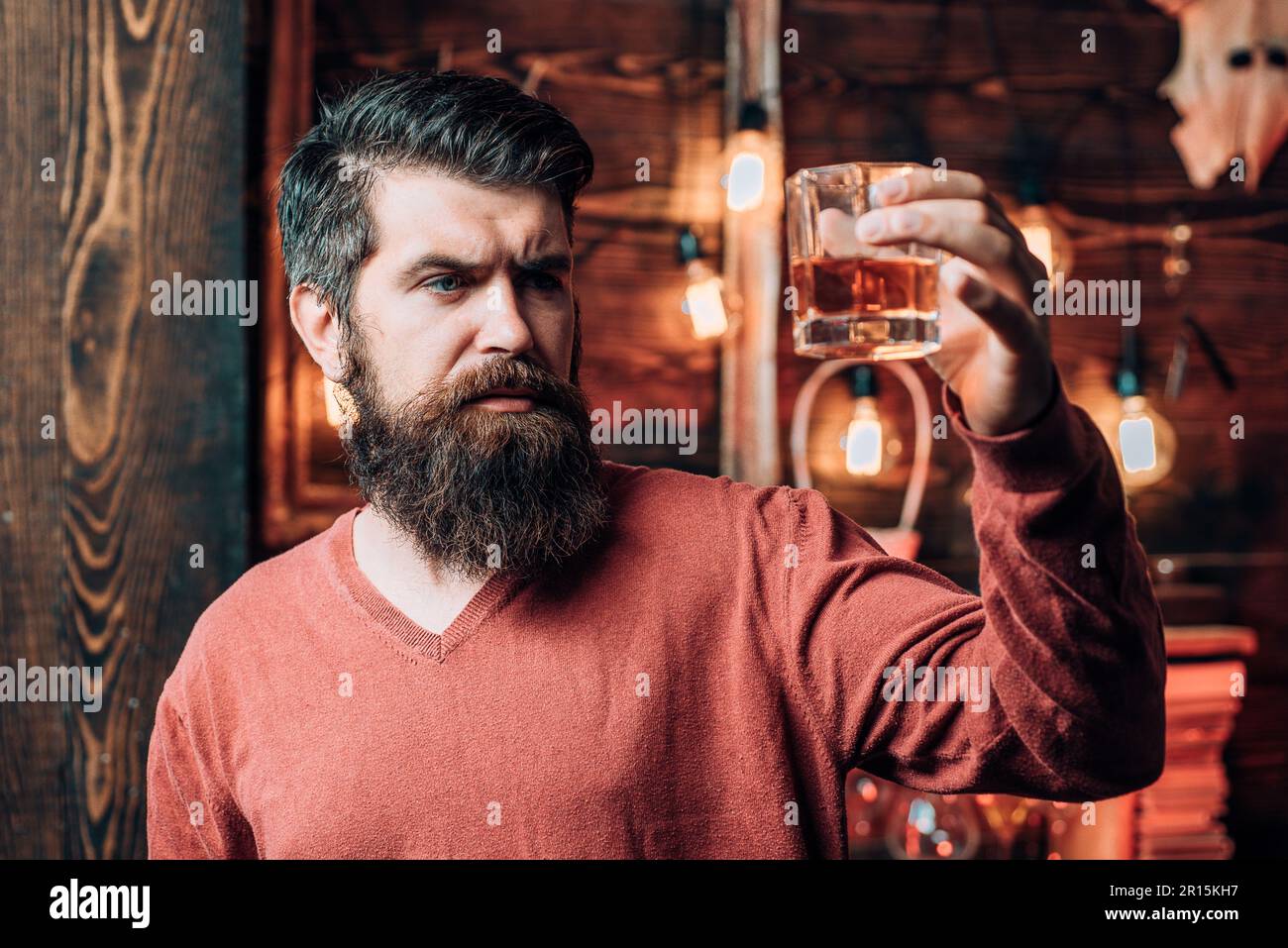 Handsome pensive man is holding a glass of whiskey. Retro bar. Man in ...