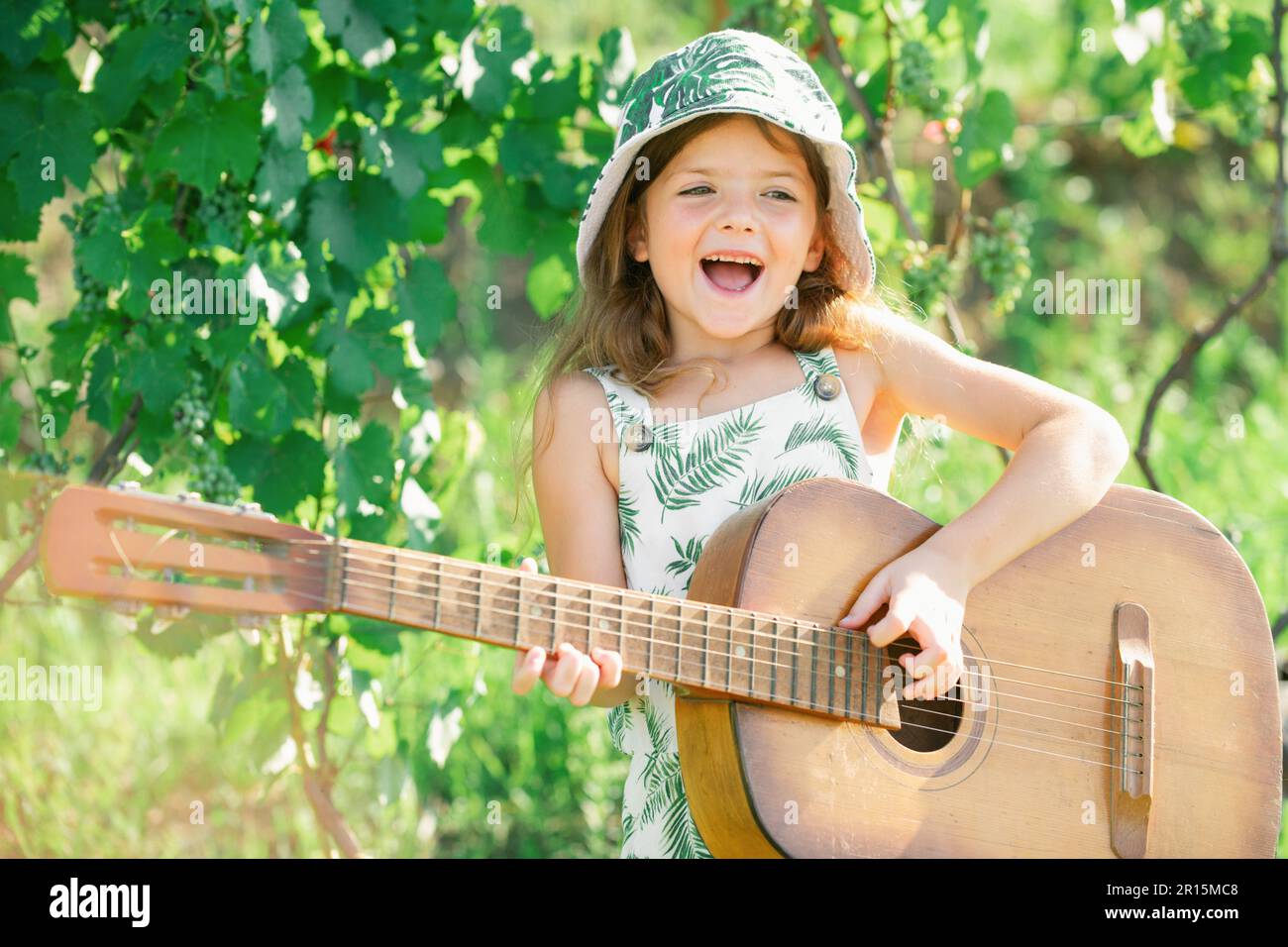 Child musician playing guitar. Stylish little child girl wearing a ...