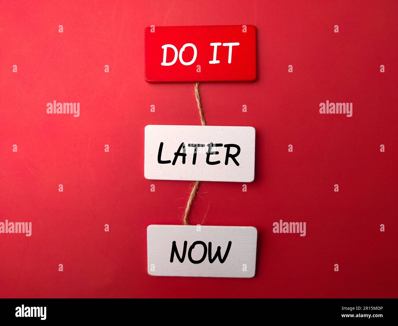 Colored wooden board with the word DO IT LATER NOW on a red background ...
