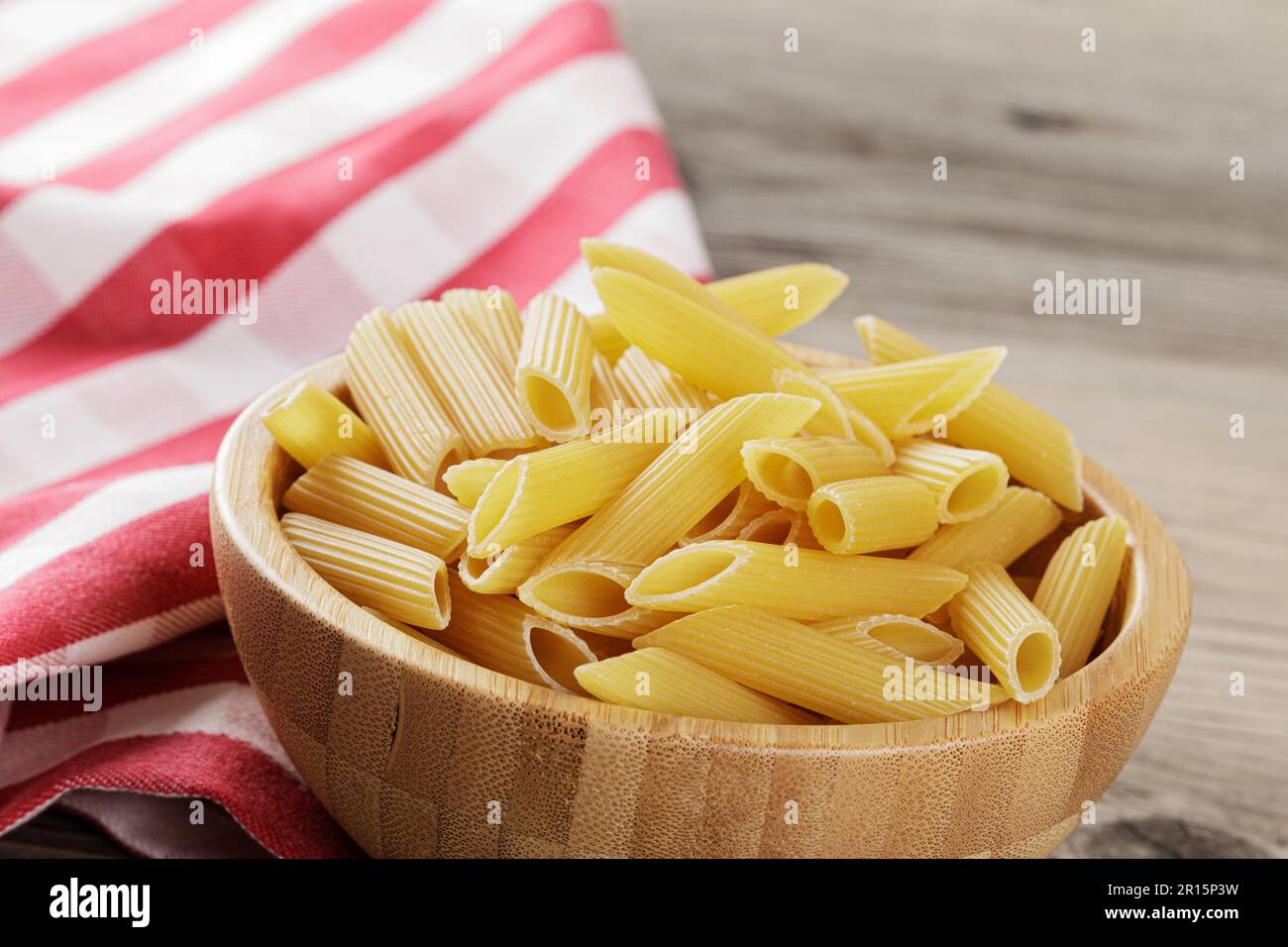 Raw Penne Rigate noodles isolated on a gray wooden background Stock ...