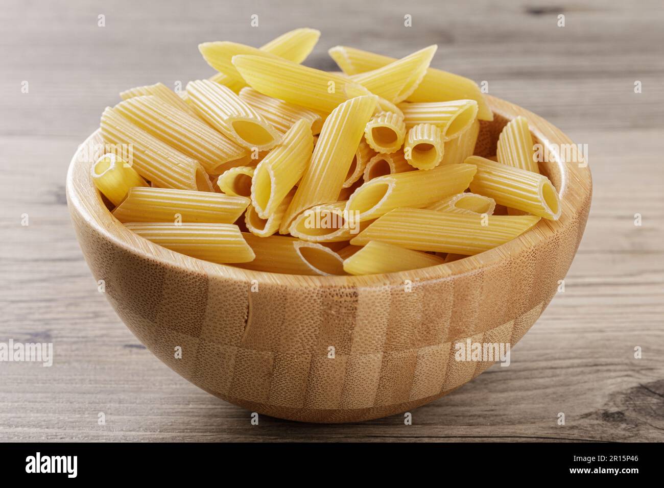 Raw Penne Rigate noodles isolated on a gray wooden background Stock ...