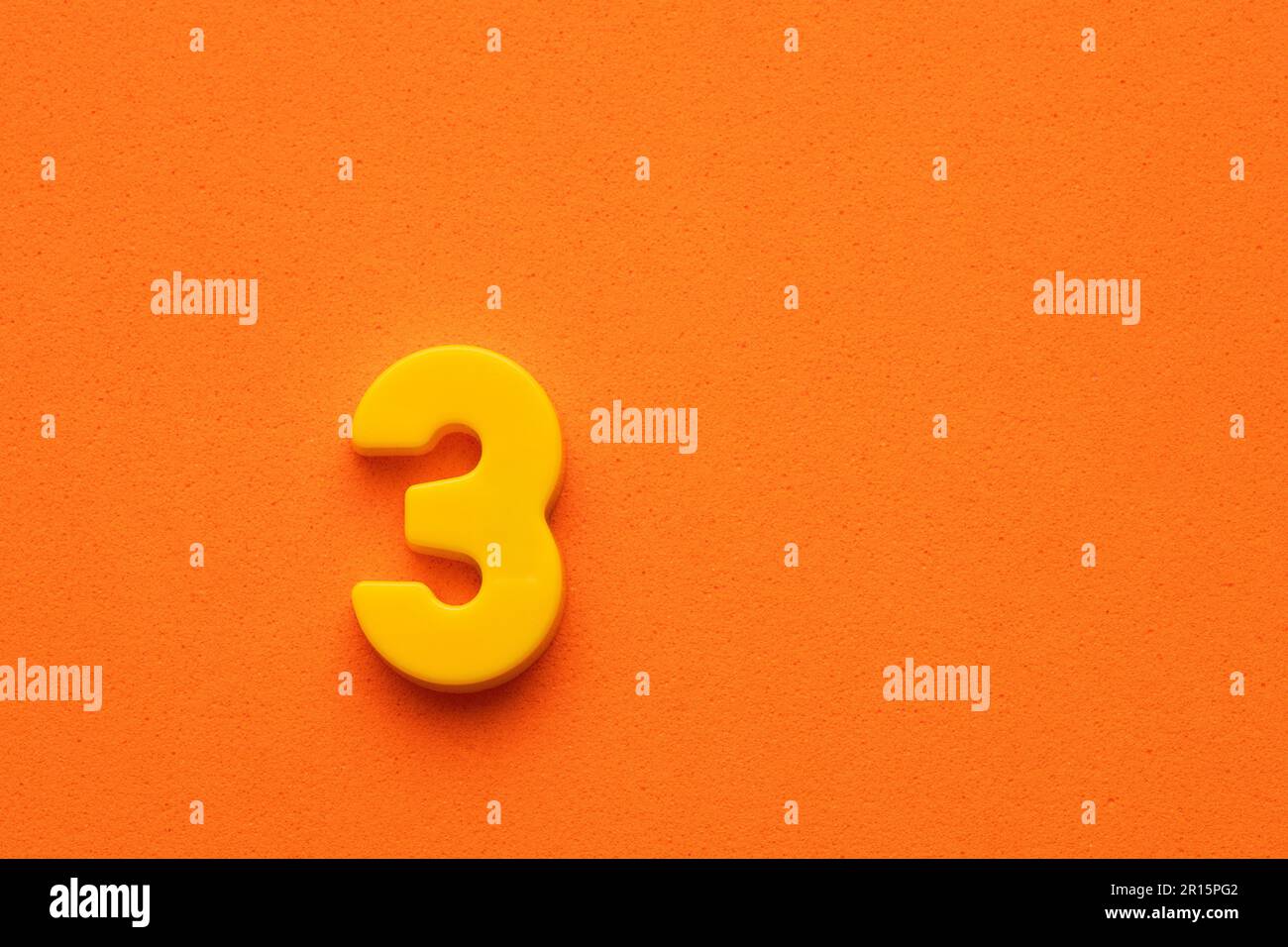 Yellow number 3 - plastic piece on orange foamy background Stock Photo ...