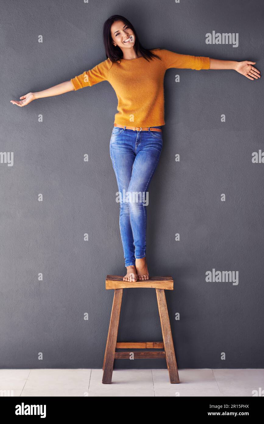 High on life. An attractive young woman standing on a stool with her ...