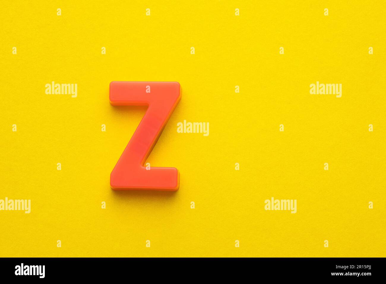 Peach colored plastic letter Z uppercase on yellow foamy background ...