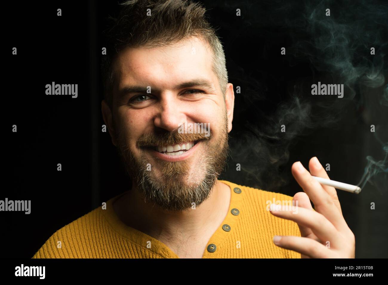 Smiling man smoking cigarette. Smoke on black background. Smoking ...