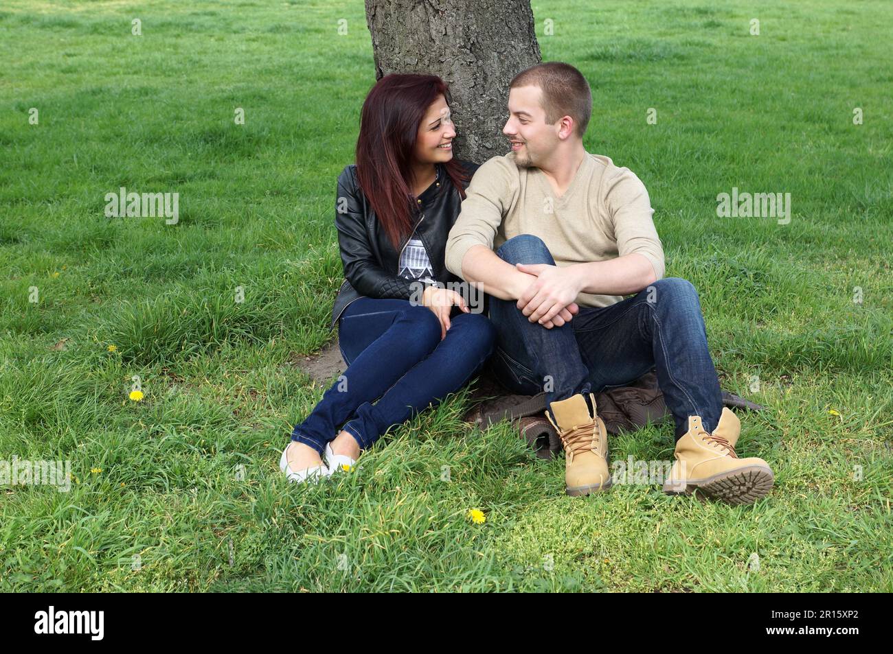 young couple relaxing under a tree Stock Photo - Alamy