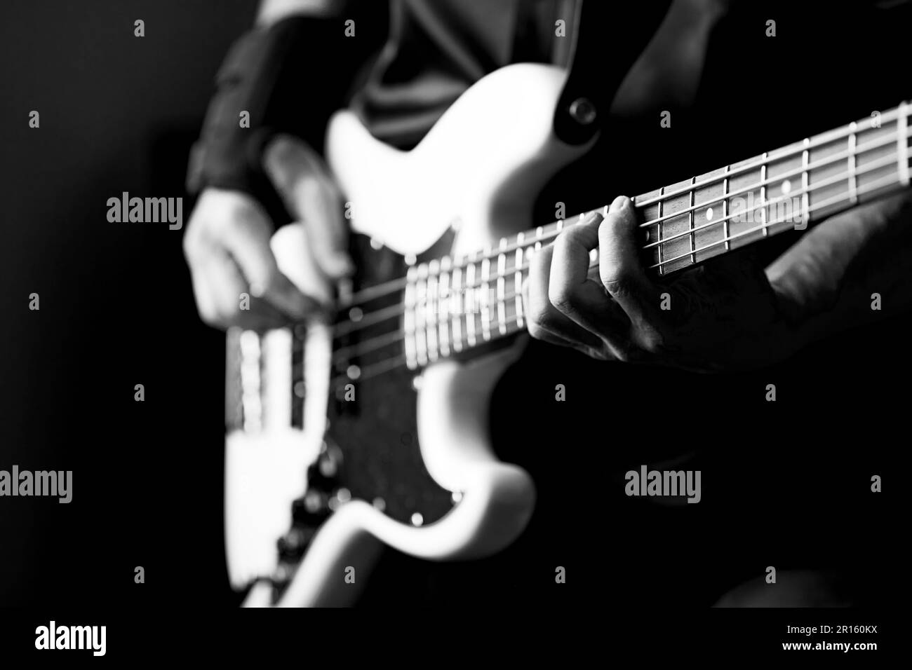 Man's hands on the strings of a bass guitar with shallow depth of field ...