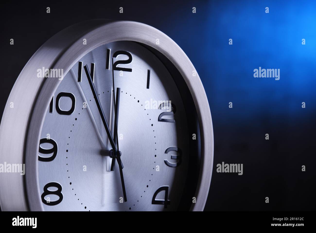 Modern wall clock showing five to twelve Stock Photo - Alamy