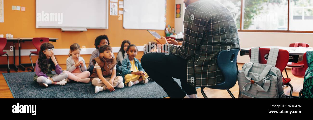 Man teaching an elementary school class using a digital tablet. Teacher ...