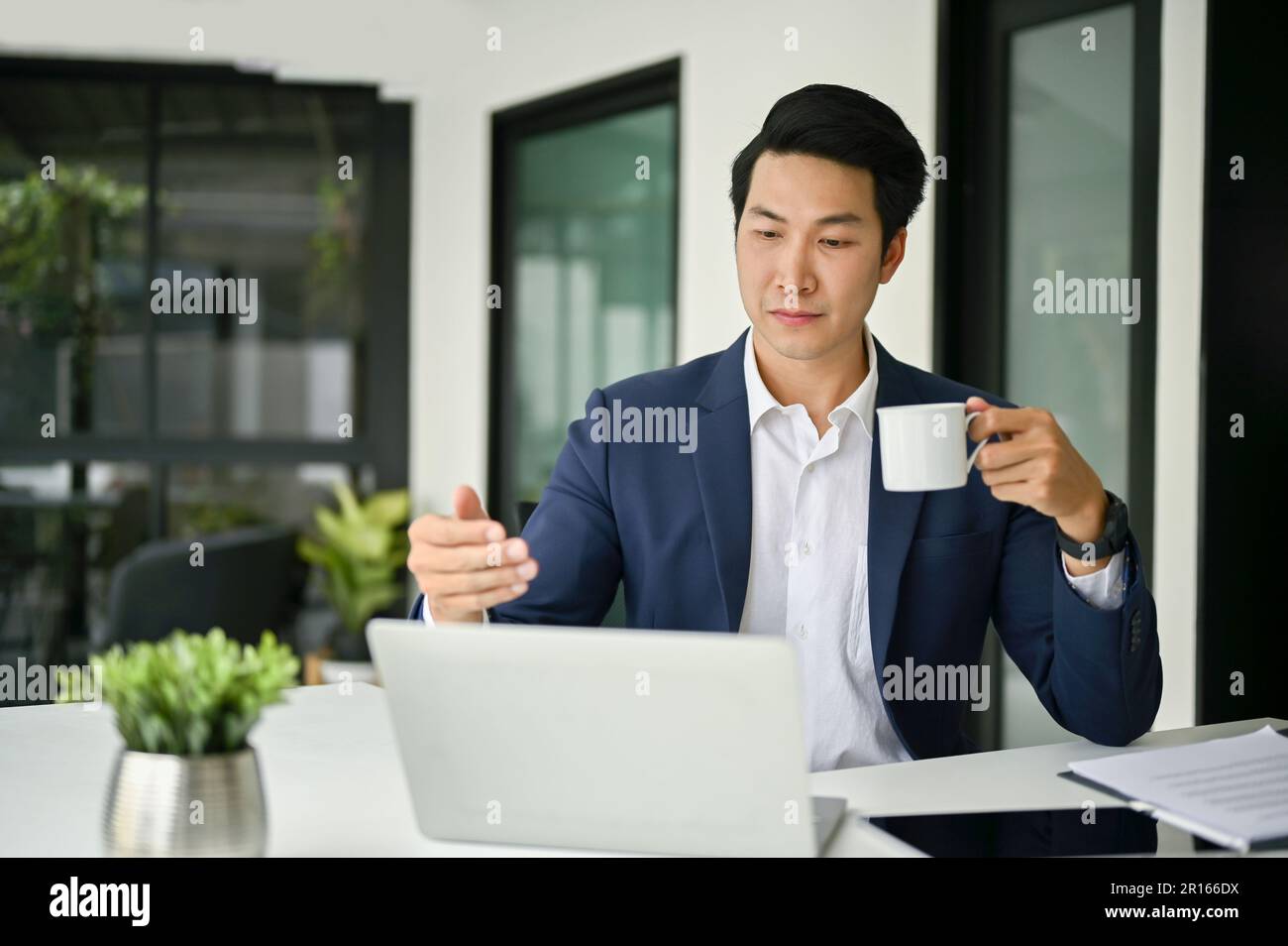 Focused and smart millennial Asian businessman or male CEO in formal ...