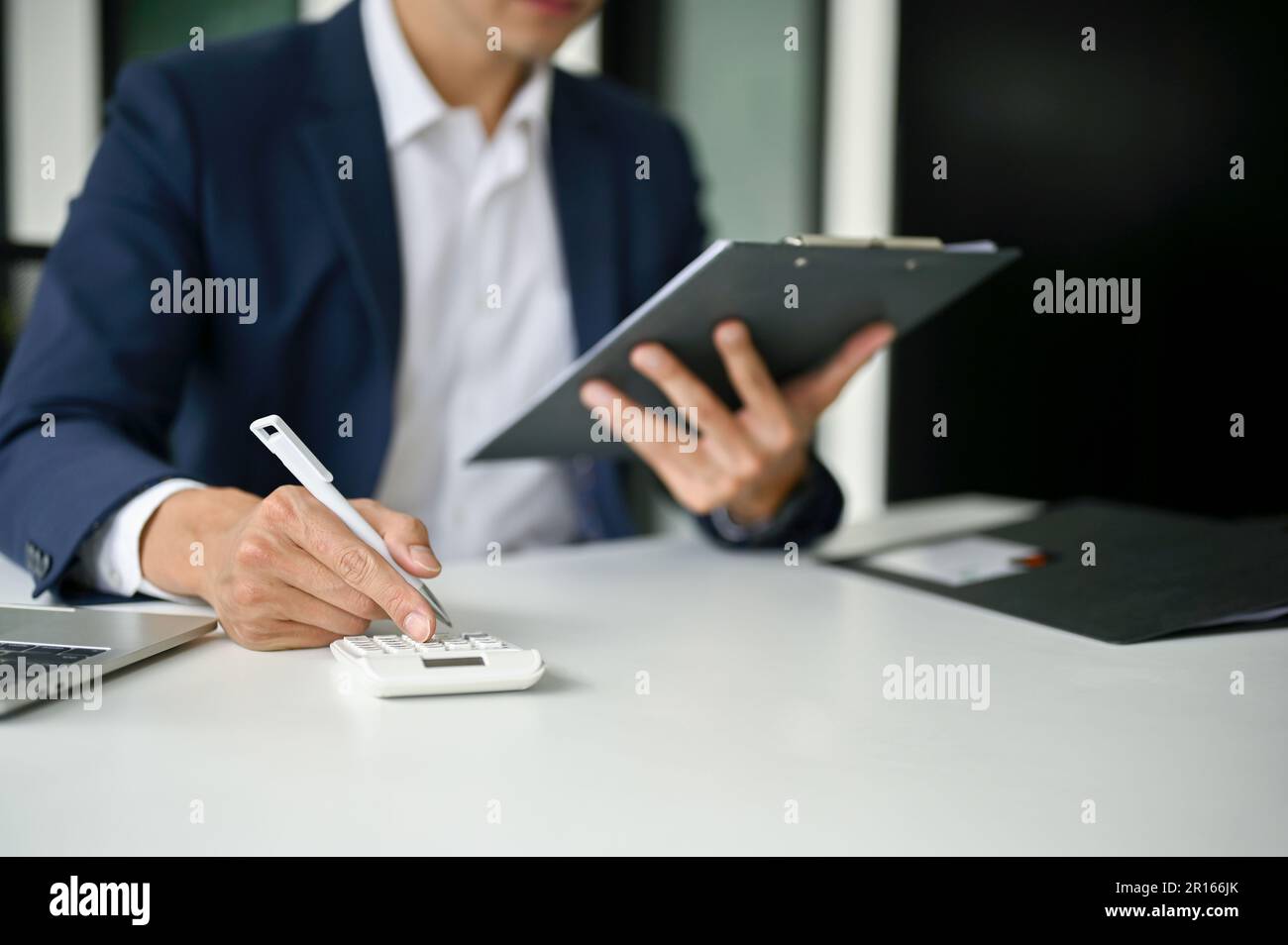 Close-up image of a professional Asian businessman using a calculator ...