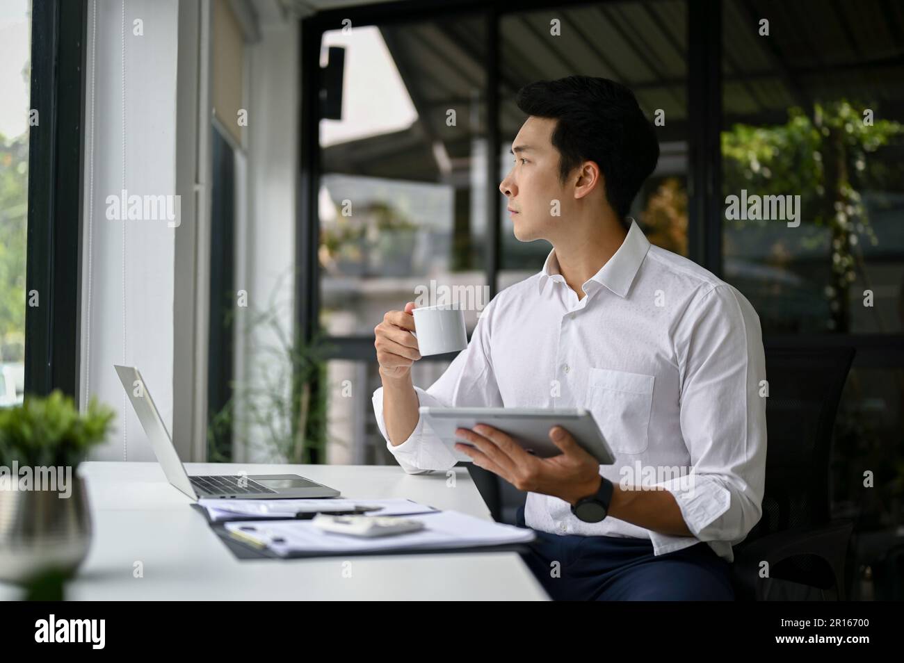 Successful millennial Asian businessman or male boss pondering ...