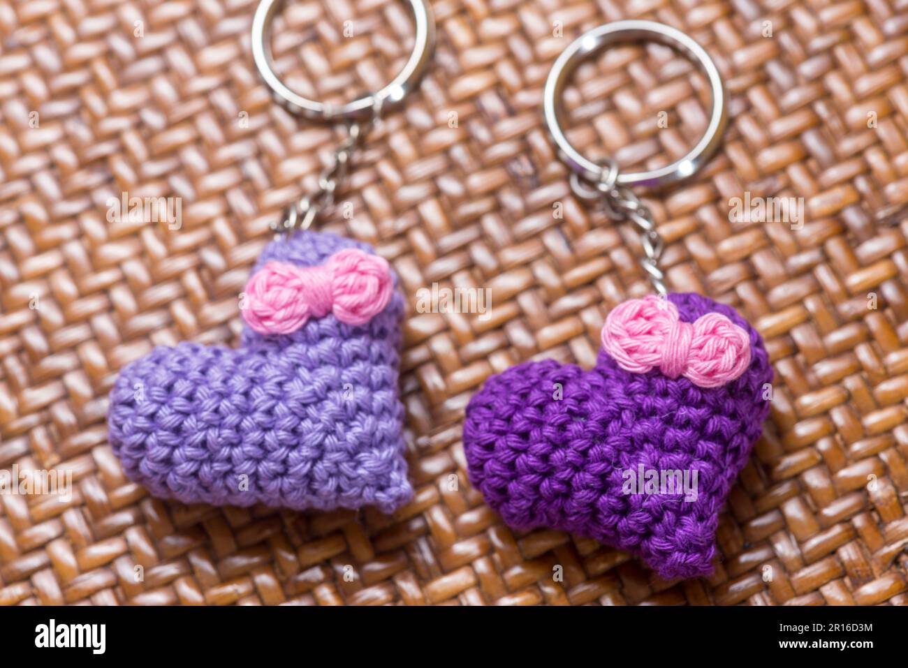 A pair of crocheted purple heart-shaped keyrings on a white background ...