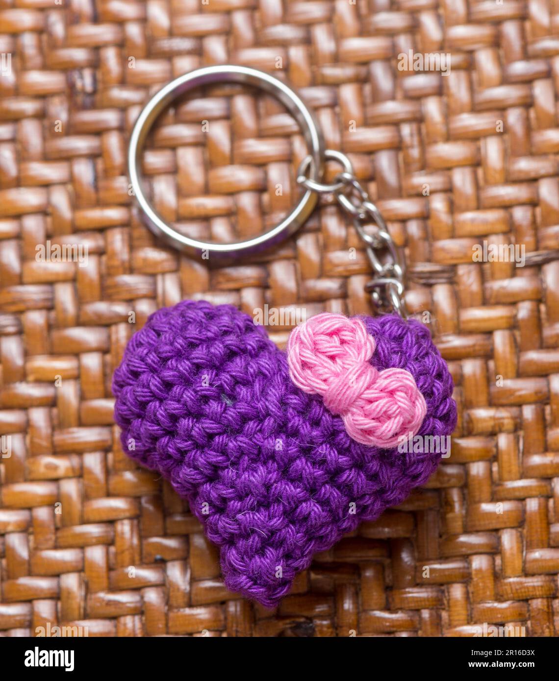 A single crocheted purple heart-shaped keyring on a textured background ...