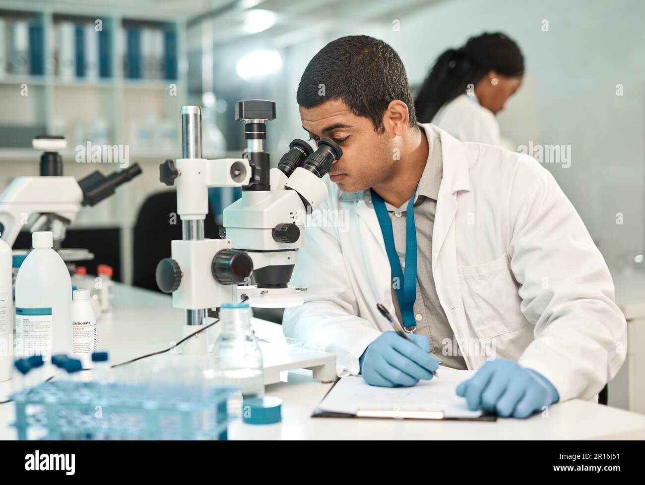 Lets investigate further. a young scientist writing notes while using a ...