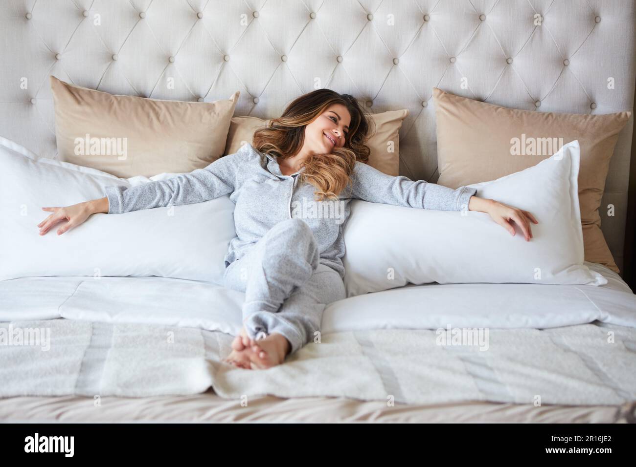 Life is more peaceful in pyjamas. a beautiful young woman waking up in ...
