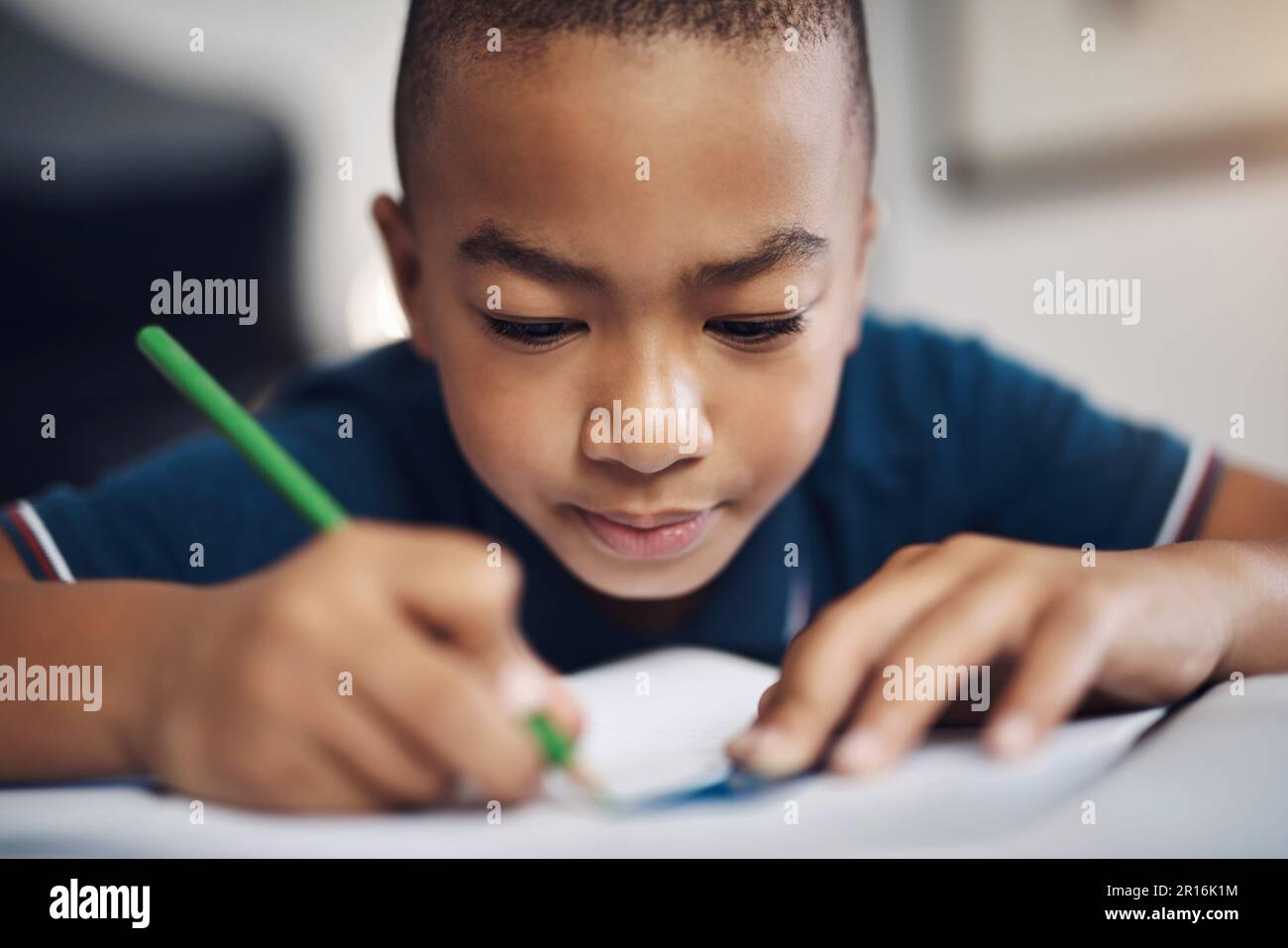 Getting his homework done before playtime. a young boy using colouring ...