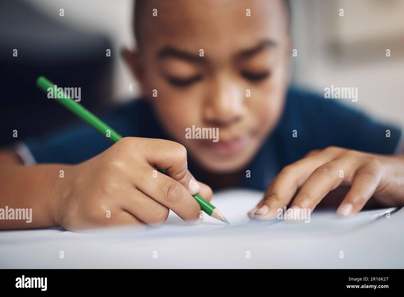 Im making a drawing for my teacher. a young boy using colouring pencils ...