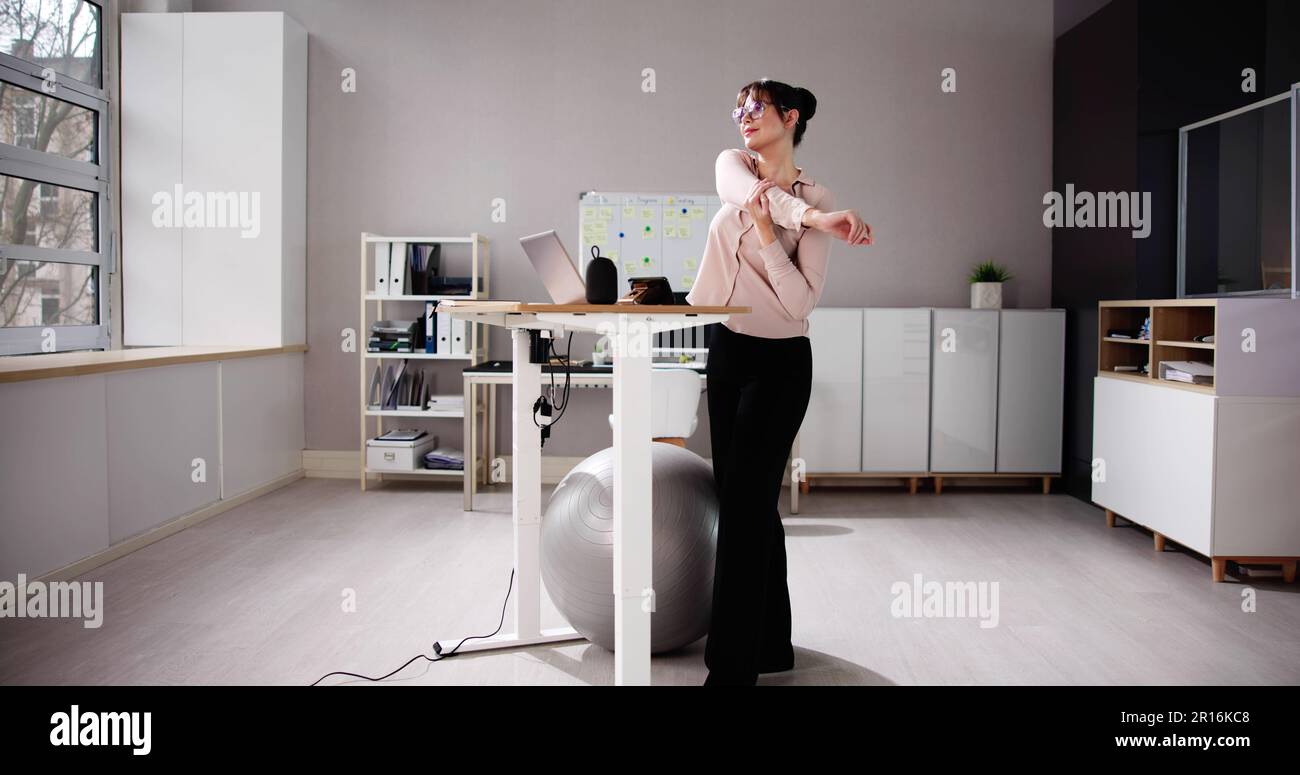Woman Using Adjustable Height Standing Desk In Office For Good Posture ...