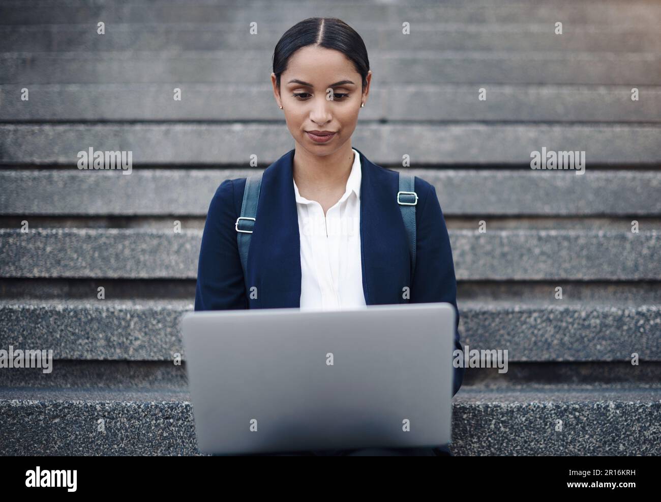 No desk, no problem. a young businesswoman using a laptop on the stairs ...