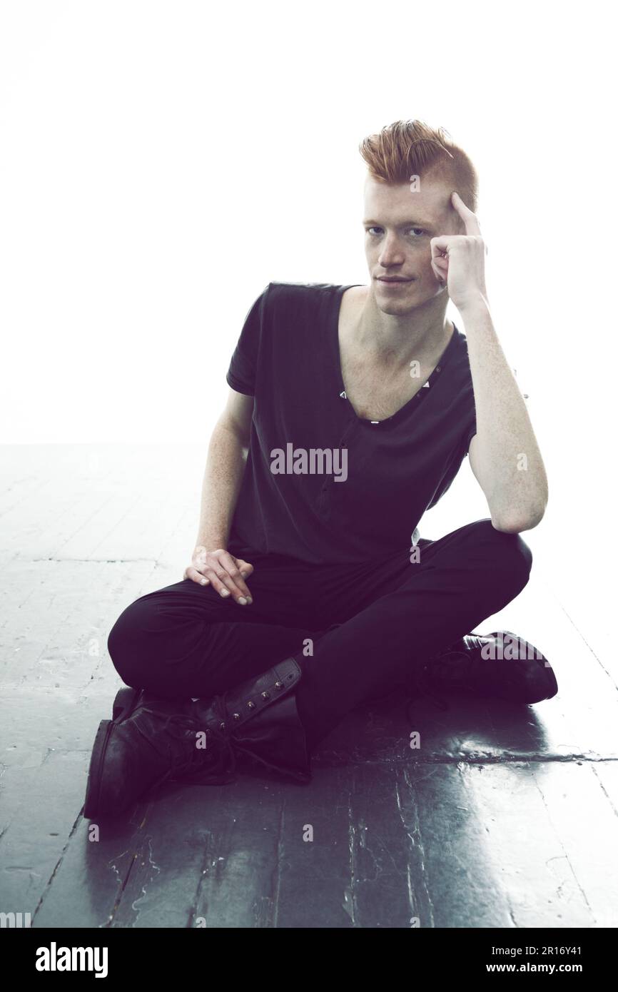 Portrait, ginger and man sitting on a floor with hand on head or ...