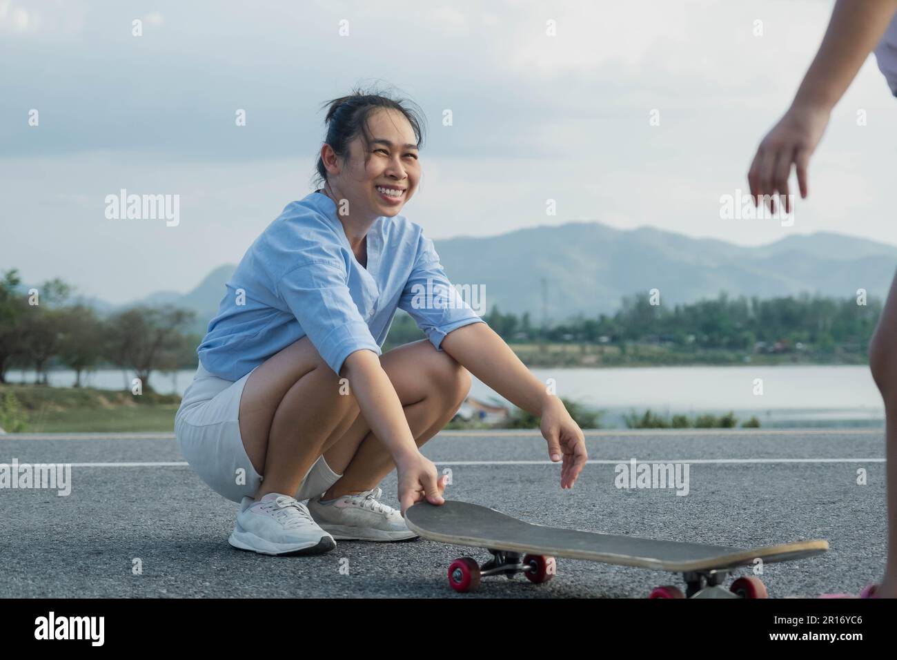 Mother teaching her daughter how to skateboard in the park. Child ...